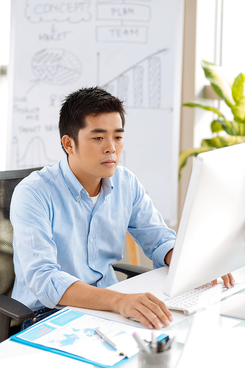 Hard-working Asian manager wearing blue shirt sitting in front of ...