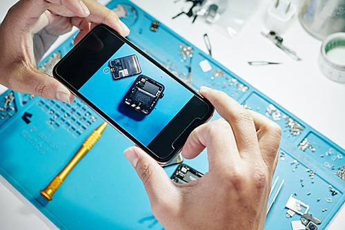 Hands of man photographing disassembled smartwatch after installing ...
