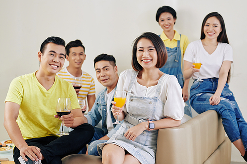 Group of happy Vietnamese friends sitting on sofa at home and posing ...