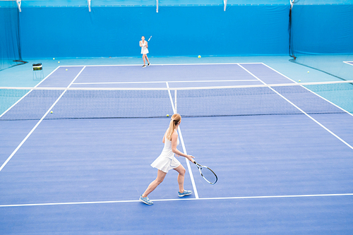 Wide angle portrait of two female players playing tennis in indoor ...