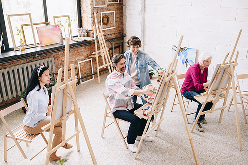 Wide angle portrait of female art teacher working with group of ...