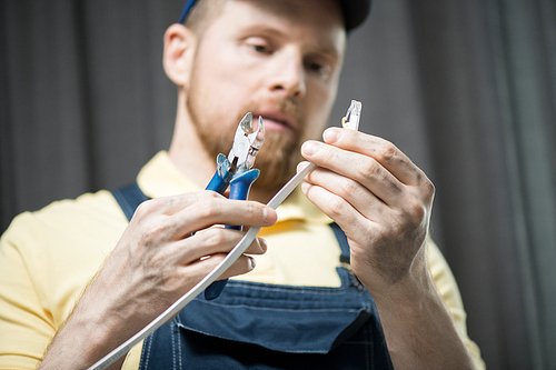 유토이미지 | Close-up of concentrated young man checking power cable: he ...