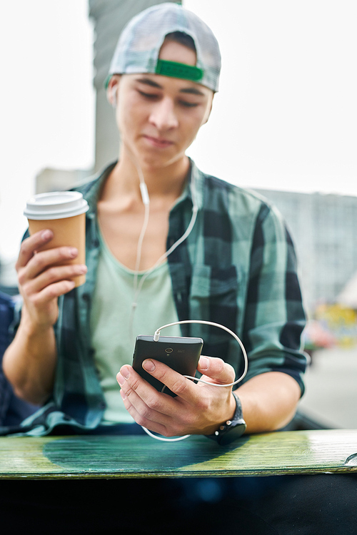 Portrait of contemporary teenager using smartphone outdoors, focus on ...