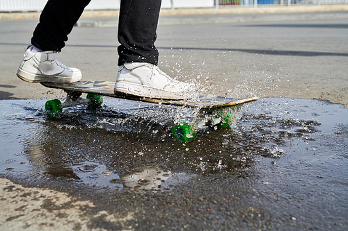 Low section portrait of unrecognizable teenager riding skateboard over ...