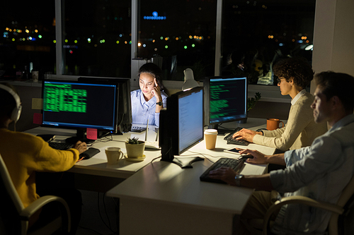 유토이미지 | Group of computer programmers working at night in dark office, copy space