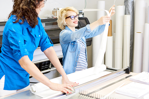 Portrait of two female operators in modern printing shop or publishing ...