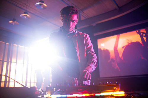 Portrait shot of handsome young DJ mixing music on console while ...