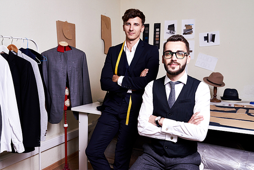 Portrait of two handsome young tailors posing in traditional atelier ...