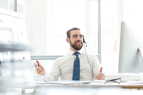 유토이미지 | Positive confident handsome hotline operator with beard sitting ...
