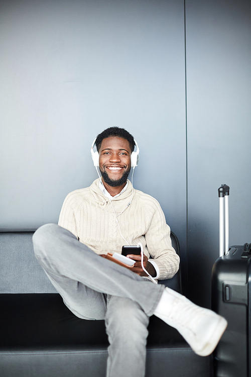 Young cheerful man in casualwear looking at you while sitting in lounge ...