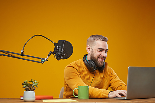 Horizontal medium studio shot of happy young Caucasian man typing ...
