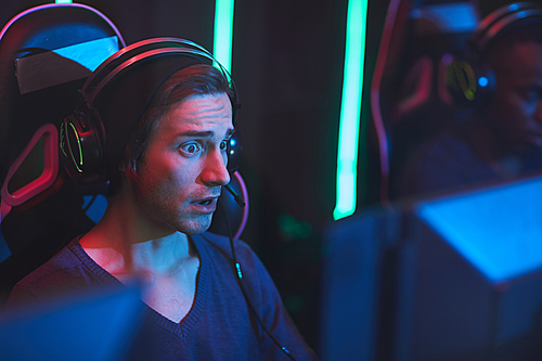 Shocked expressive young gamer with frowning forehead wearing headset ...