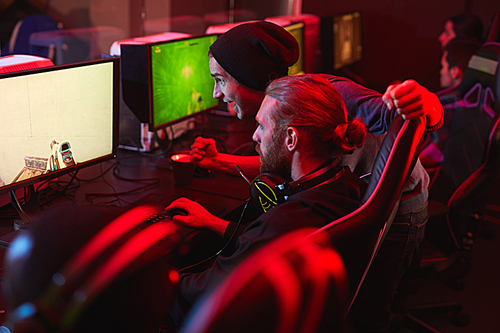 Positive excited hipster guys playing computer game together in modern ...