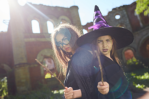 Portrait of two little witches posing outdoors on Halloween pointing ...