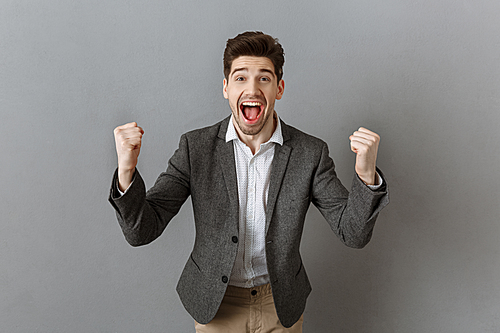 portrait of excited businessman gesturing and against grey wall ...