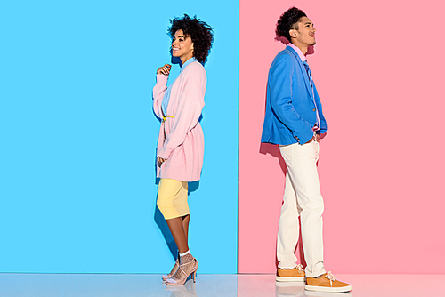 Happy couple standing back to back on pink and blue background | 유토이미지 ...