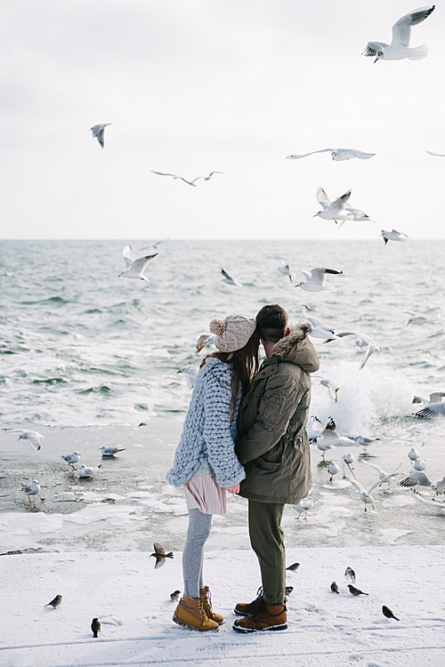 young couple holding hands on seashore and looking on seagulls | 유토이미지 ...