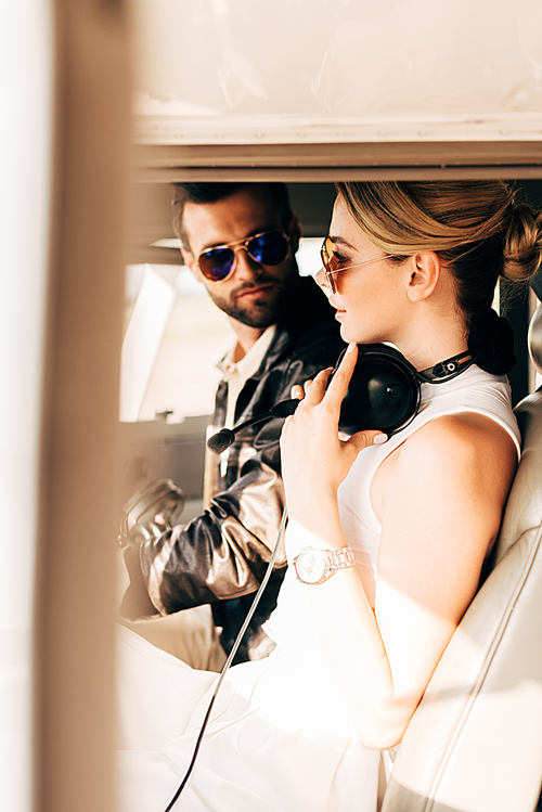 side view of serious male pilot in sunglasses sitting with girlfriend ...