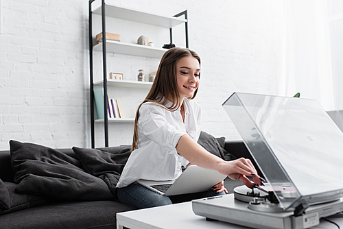 유토이미지 | smiling girl in white shirt sitting on couch with laptop and ...
