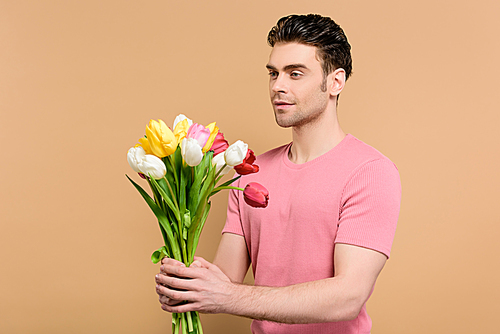handsome man looking at bouquet of tulips isolated on beige | 유토이미지 ...