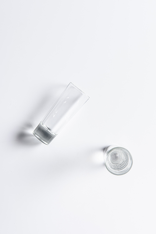 top view of one glass with water and one empty glass on white table ...