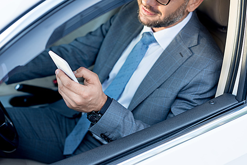 유토이미지 | cropped shot of businessman using smartphone while driving car