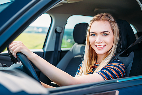 유토이미지 | close up shot of smiling young woman sitting behind car wheel