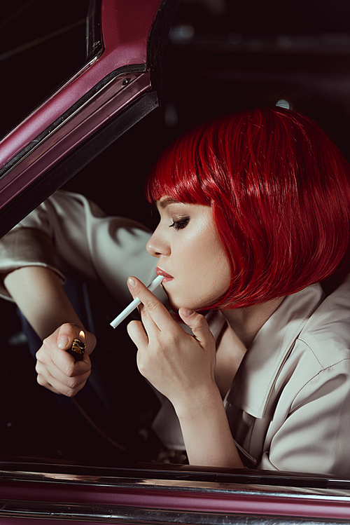 side view of beautiful young woman in red wig smoking cigarette in car ...