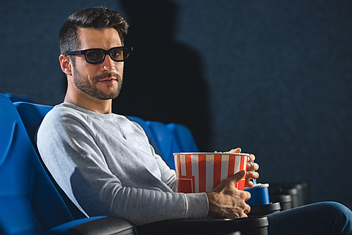 유토이미지 | side view of young man in 3d glasses with popcorn in cinema