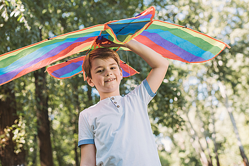유토이미지 | low angle view of cute happy boy holding kite and smiling at ...