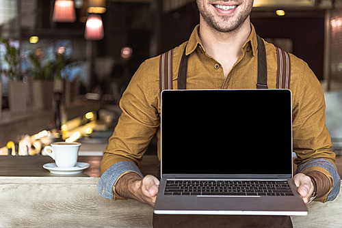happy young waiter holding laptop with blank screen in cafe | 유토이미지 ...