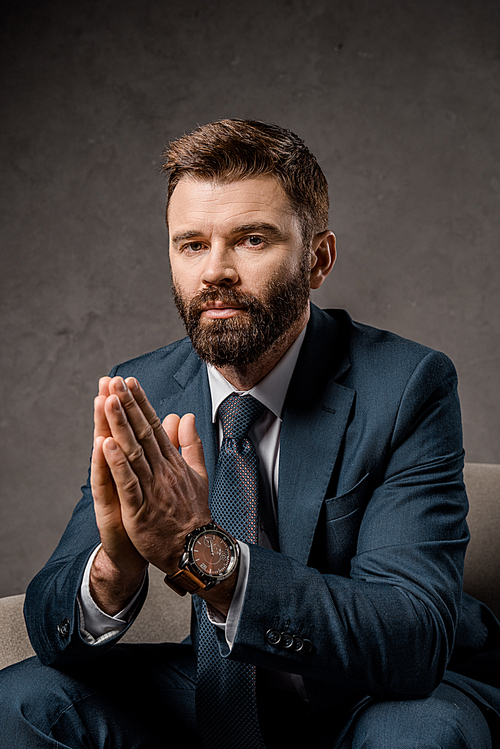 close up of handsome businessman sitting in armchair with praying hands ...
