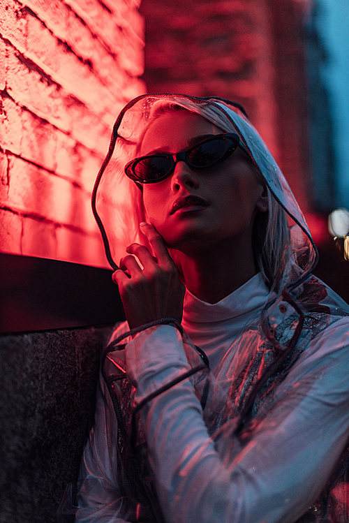 beautiful young woman in transparent raincoat and sunglasses on street ...