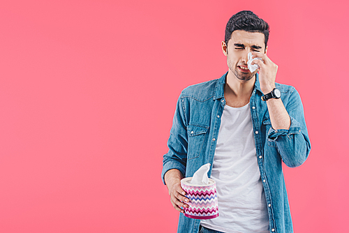 sad young man with tissue box crying and wiping tears isolated on pink ...