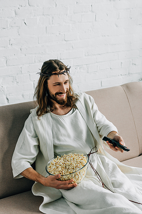 high angle view of happy Jesus in crown of thorns watching tv and ...