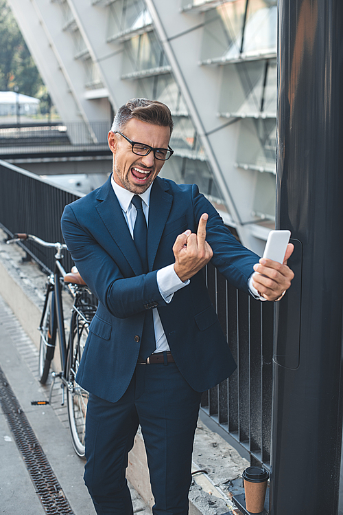 emotional middle aged businessman in formal wear and eyeglasses holding ...