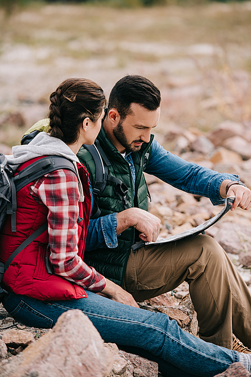 유토이미지 | side view of hikers looking for destination on map while ...