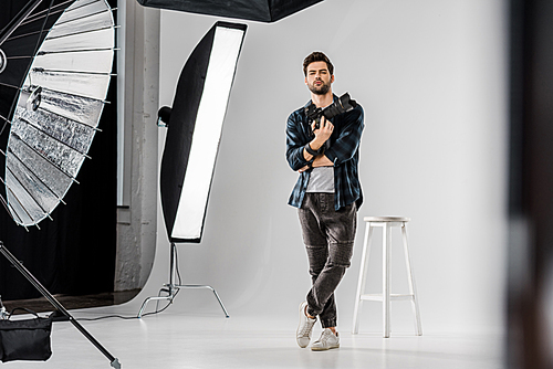 full length view of confident young photographer holding professional ...