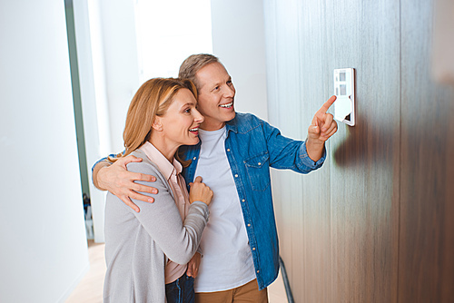 happy man pointing at smart home control panel while hugging wife | 유토 ...