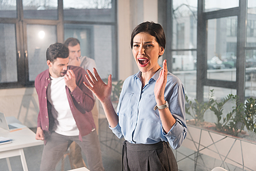 scared businesswoman standing yelling near coworkers in office with ...