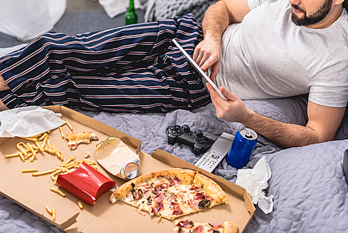 유토이미지 | cropped image of loner using tablet on bed in bedroom