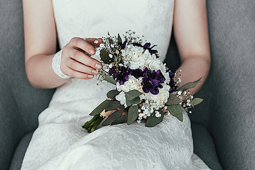 partial view of bride in white dress with beautiful bridal bouquet ...