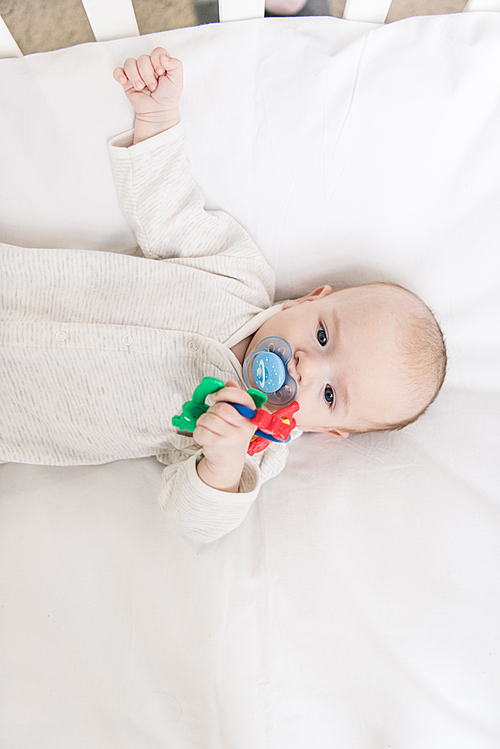 유토이미지 | overhead view of little baby with pacifier holding toy while ...