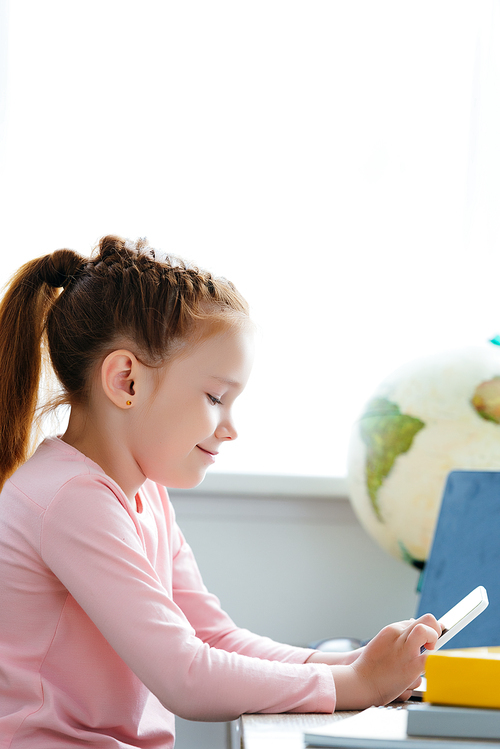유토이미지 | side view of beautiful smiling child using smartphone