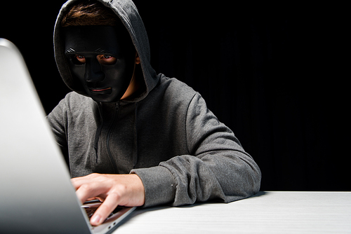 유토이미지 | anonymous internet troll in mask typing on laptop keyboard ...
