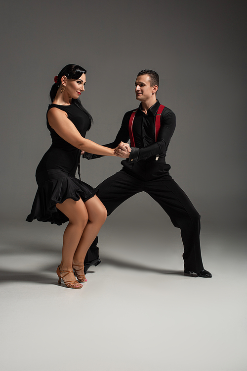 유토이미지 | two smiling dancers in black clothes performing tango on grey ...
