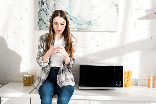 shocked woman using smartphone near microwave in kitchen | 유토이미지 | 상세 ...