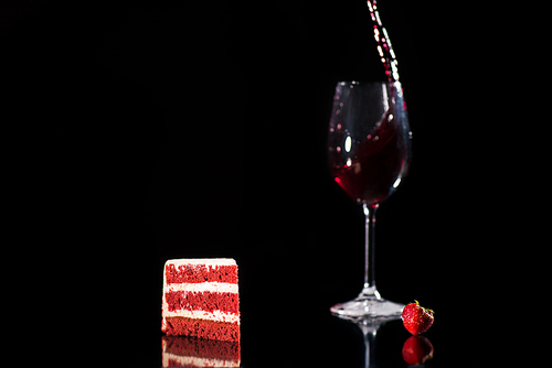 유토이미지 | piece of red and white cake near glass of wine isolated on black