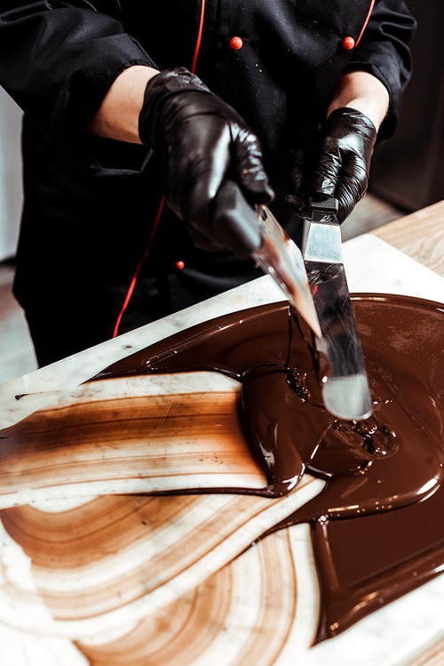 유토이미지 | cropped view of chocolatier holding cake scrapers near melted ...