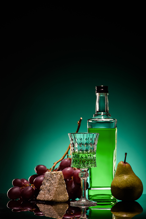 close-up shot of absinthe with fresh pear, grapes and cheese on mirror ...